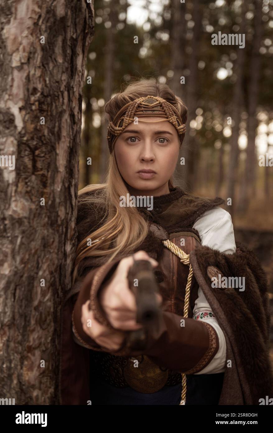 close-up of blonde girl in historical warrior costume, she aims with ...