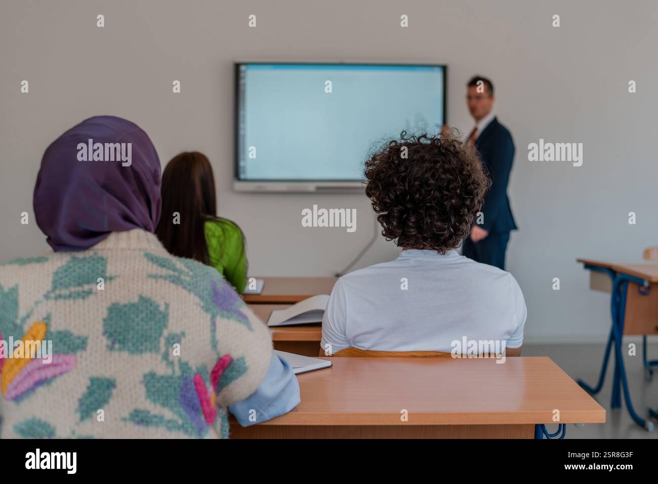 A university teacher using a smart board to explain a lesson in the ...