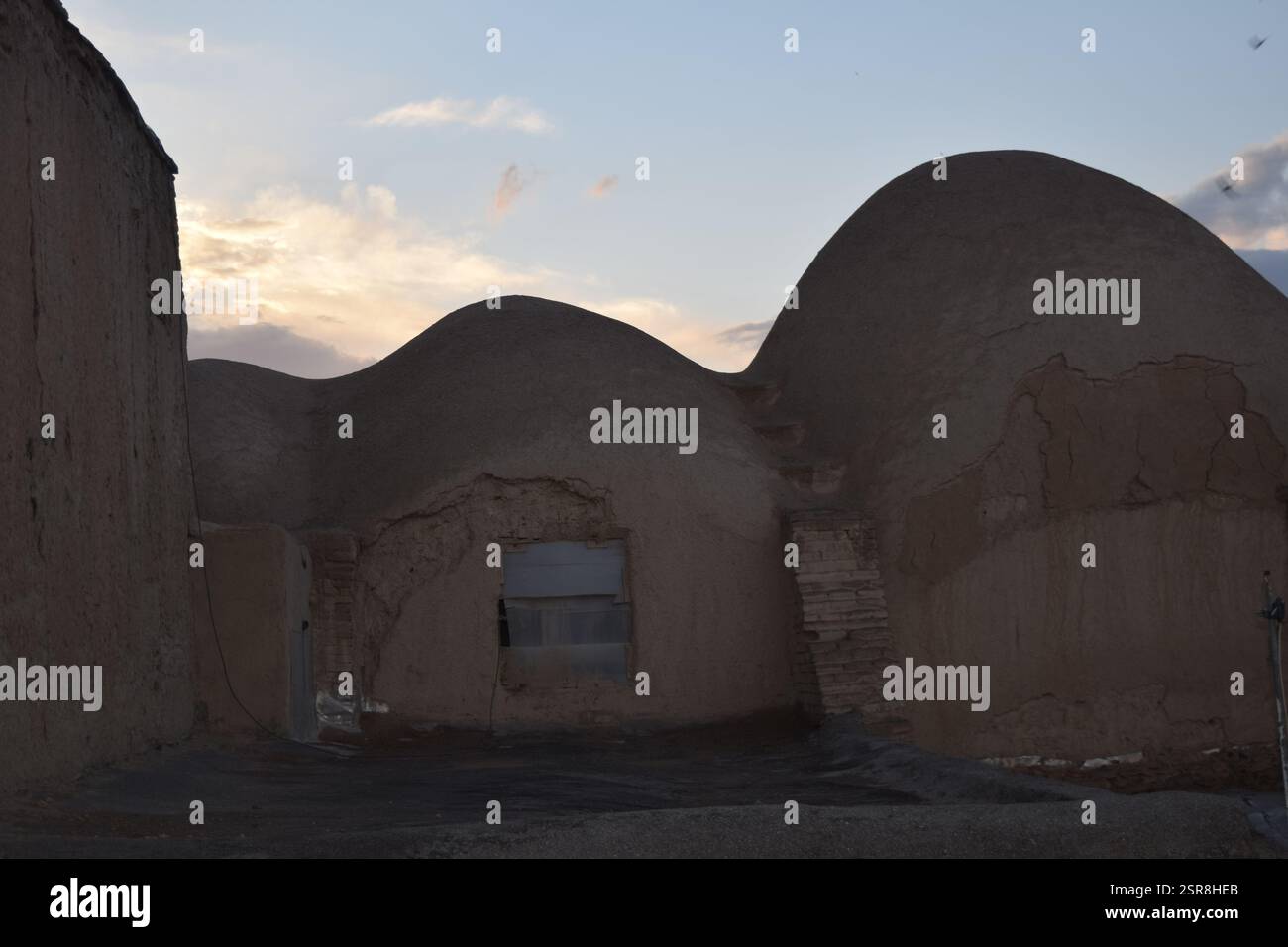 Traditional mud-brick domed house in Iran at sunset, showcasing ...
