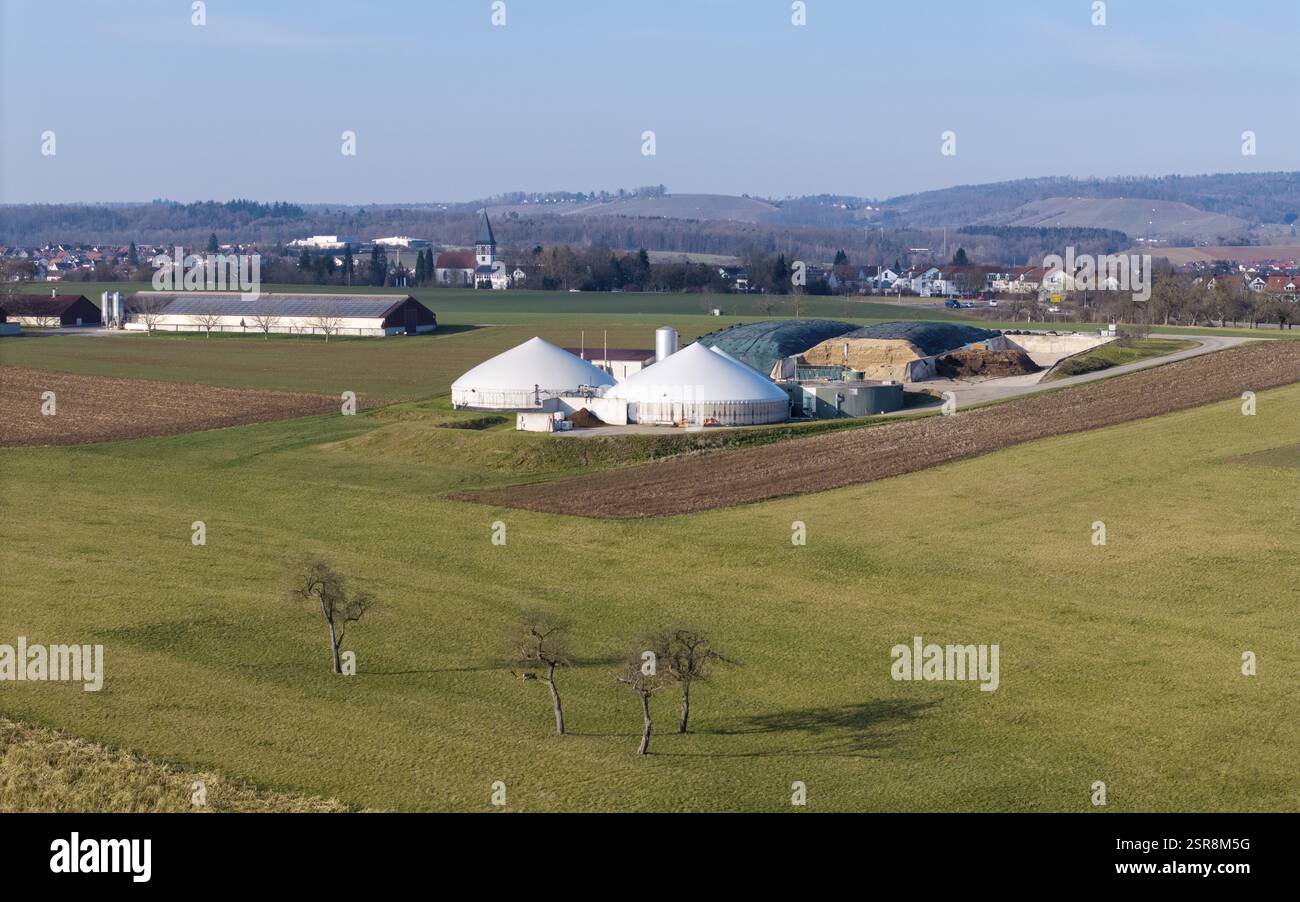 Rural scene with biogas plant, few trees and village, embedded in hilly ...
