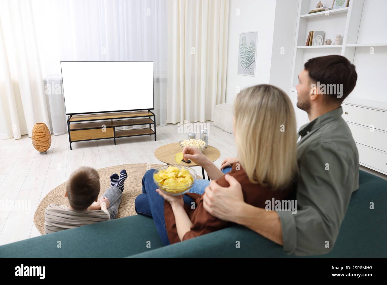 Happy family with snacks and drinks watching tv together at home Stock ...