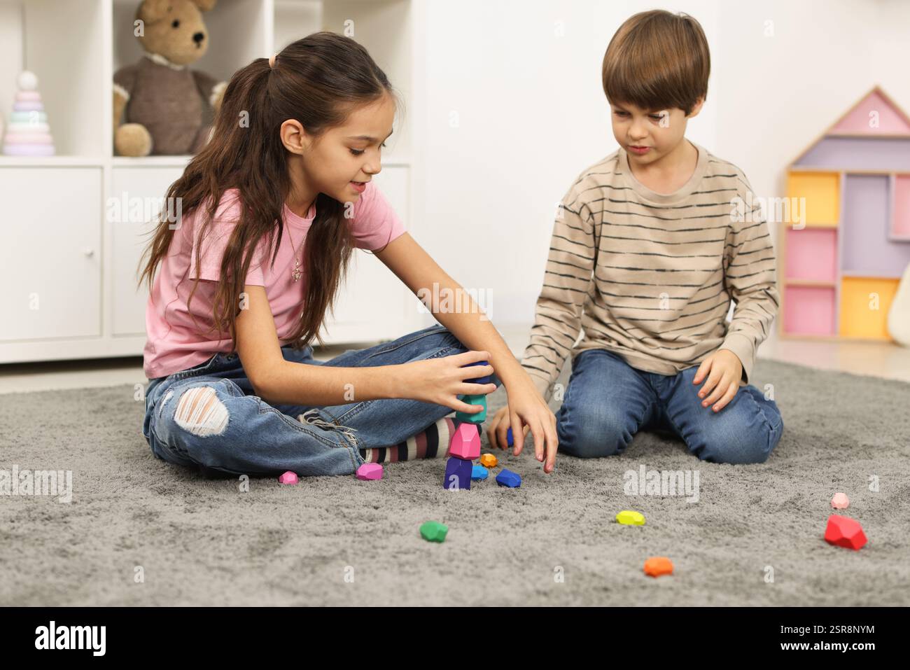 Children playing with balancing stones on floor indoors Stock Photo - Alamy