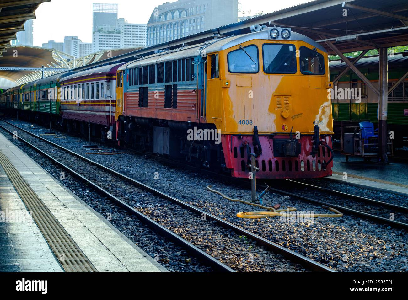 A striking yellow train stands at a railway station platform ...