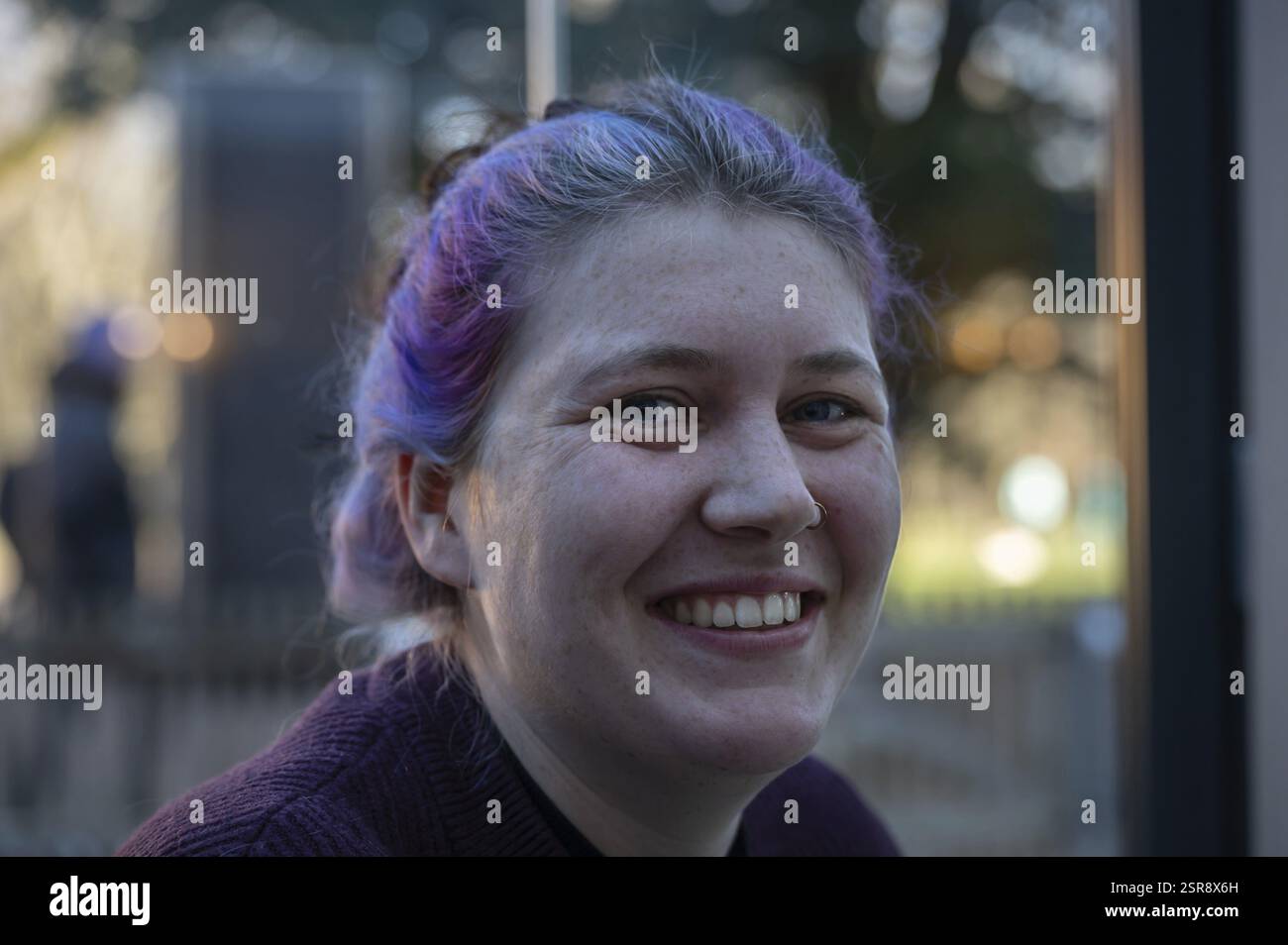 Portrait of a laughing young woman with brightly coloured hair and nose ...