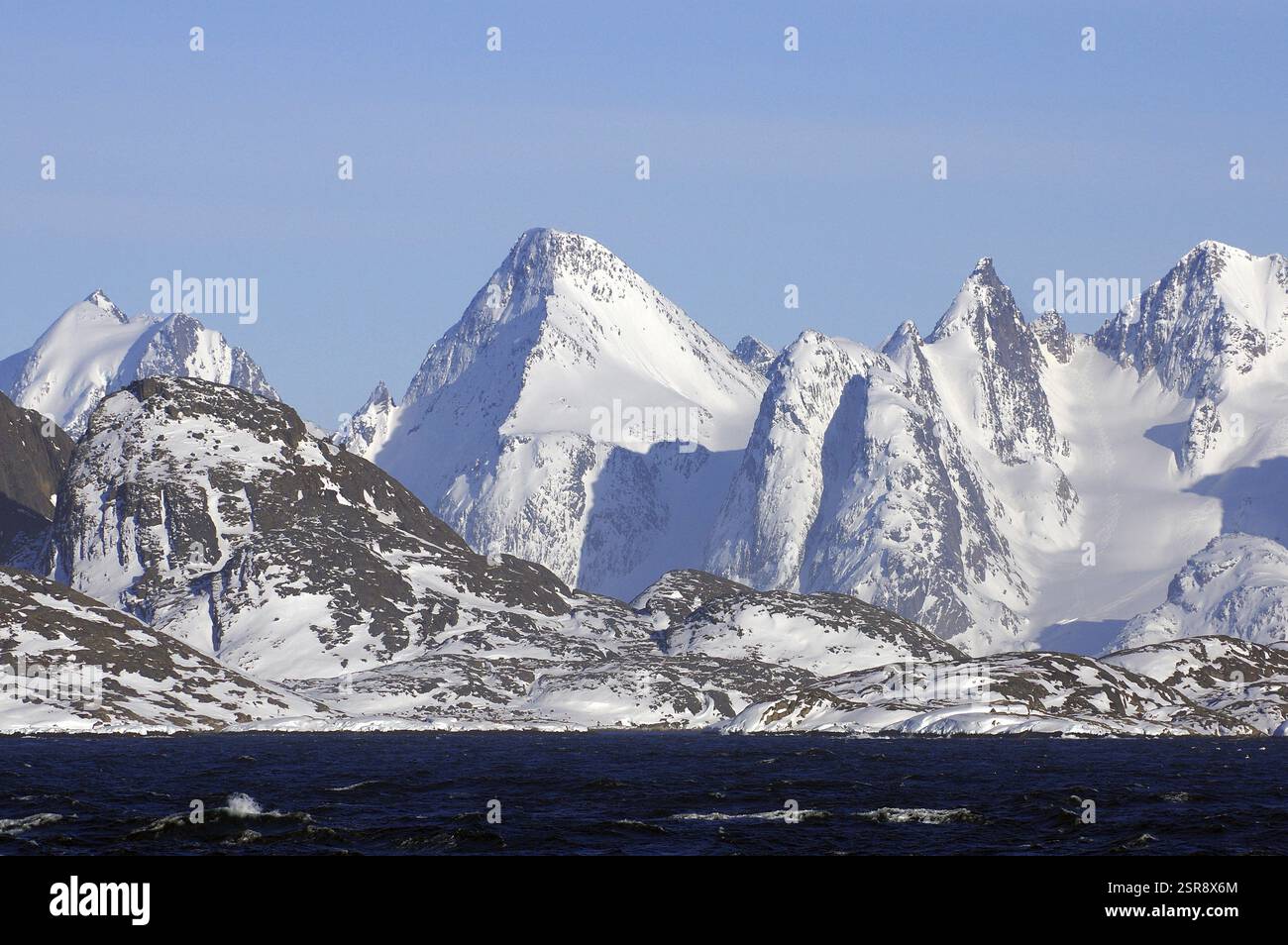 Snow and ice-covered mountains under a clear sky depicting a calm, cold ...