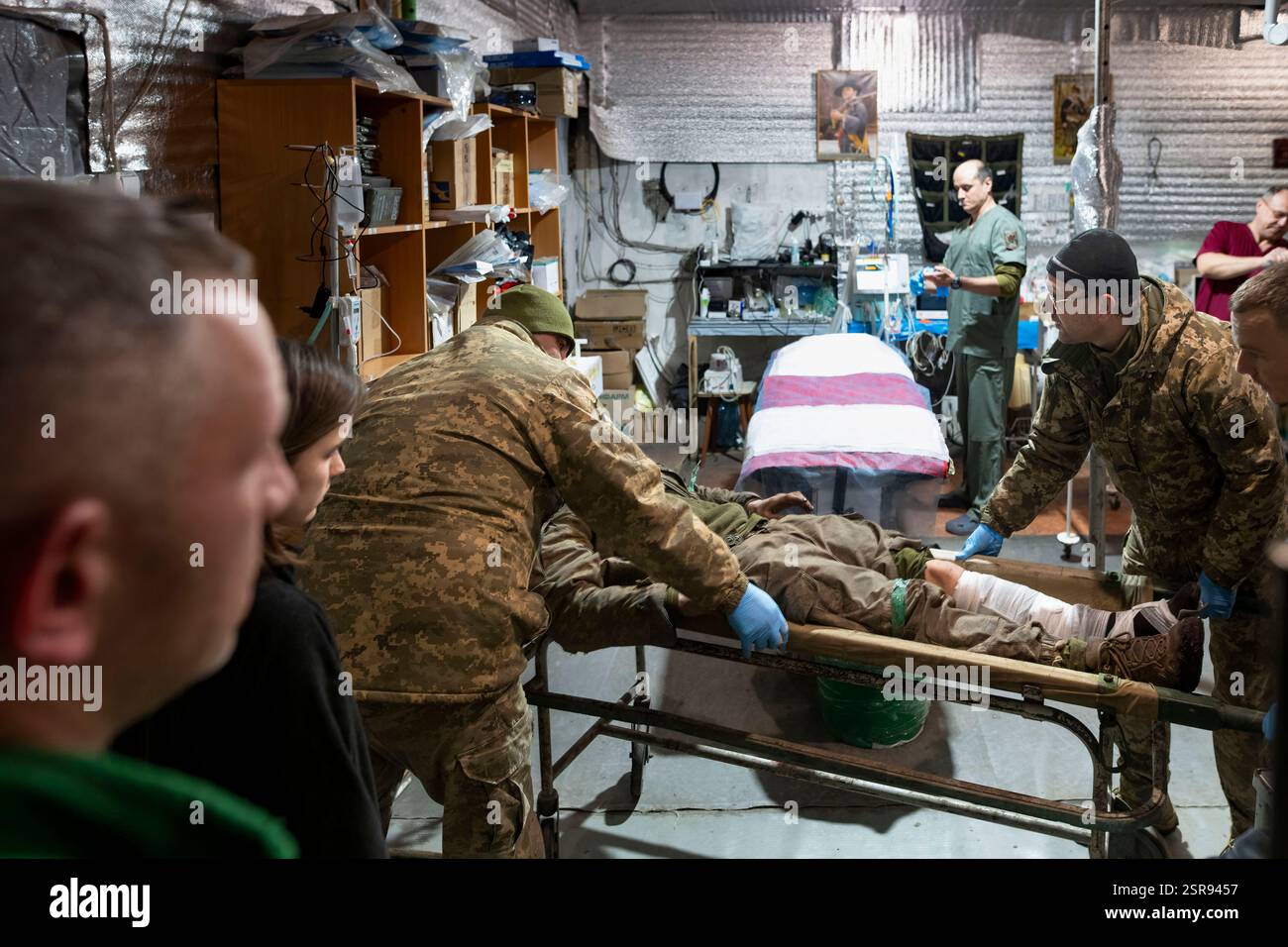 Doctors and comrades assist an injured Ukrainian soldier at an ...