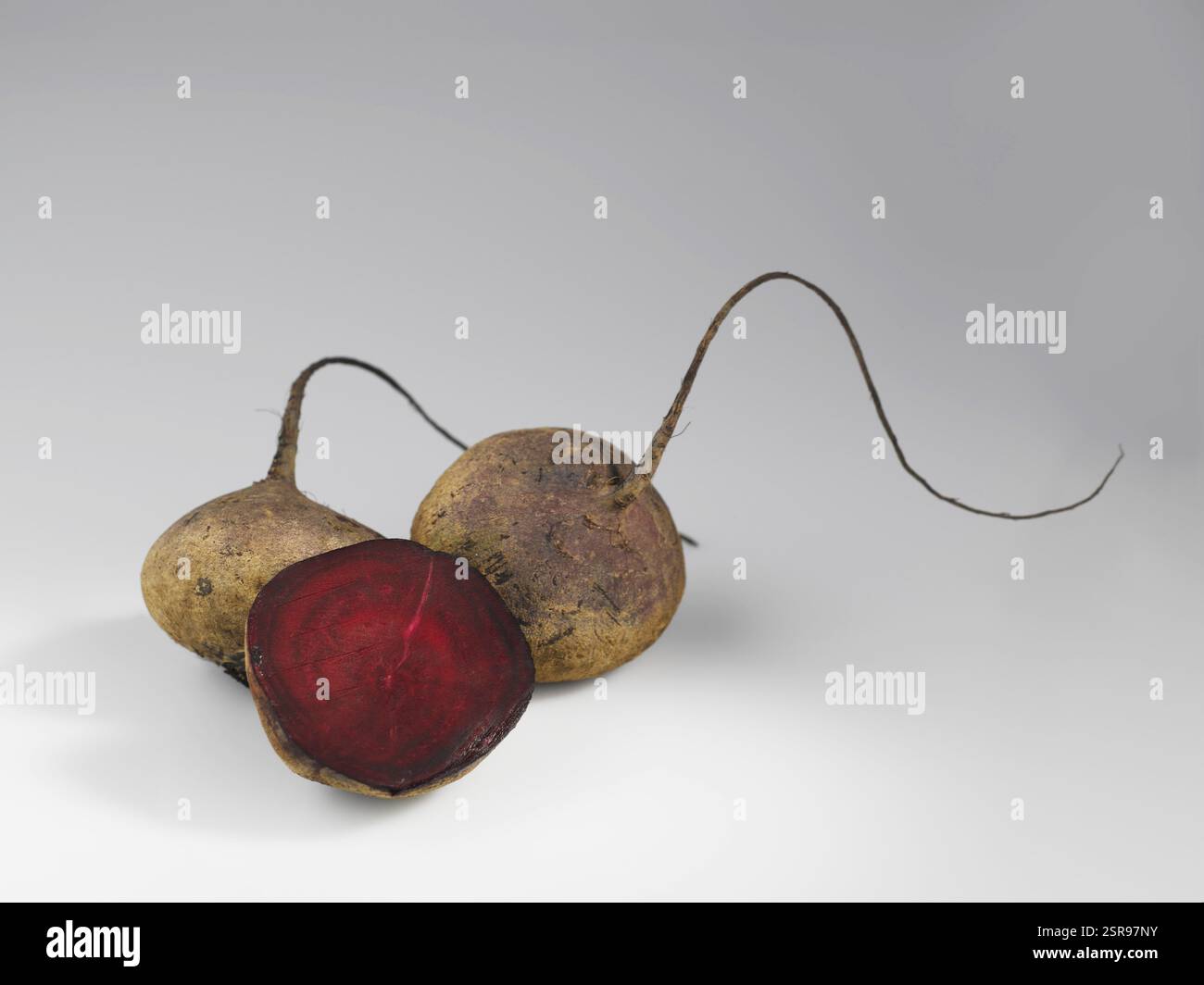 Two full and half beetroot on white background Stock Photo - Alamy