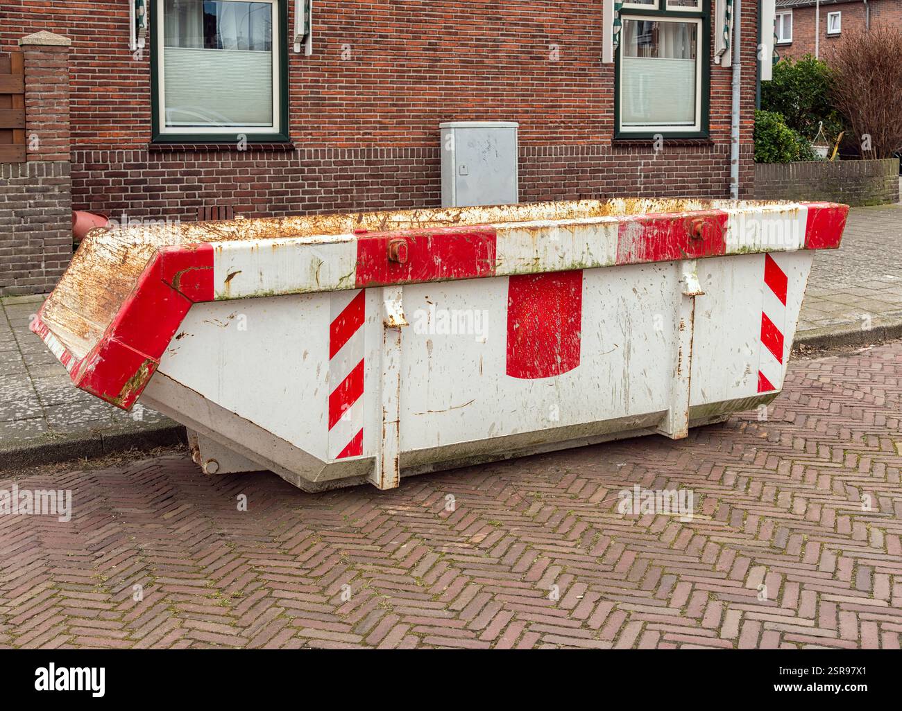 an open steel industrial waste container stands outside on the street ...
