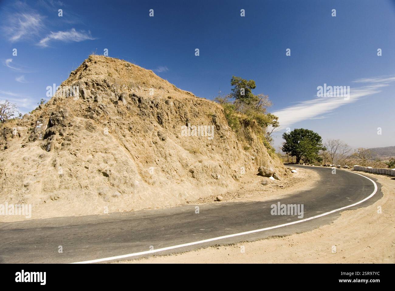 Curved road and white clouds on dark blue sky in landscape at ...