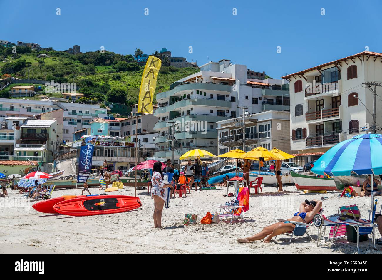 Tourists relaxing on Prainha beach shore in front of colorful umbrellas ...