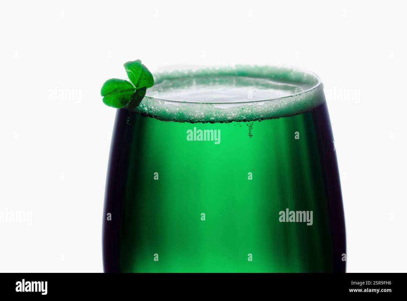A glass of green beer with a shamrock leaf on top. The drink is in a ...