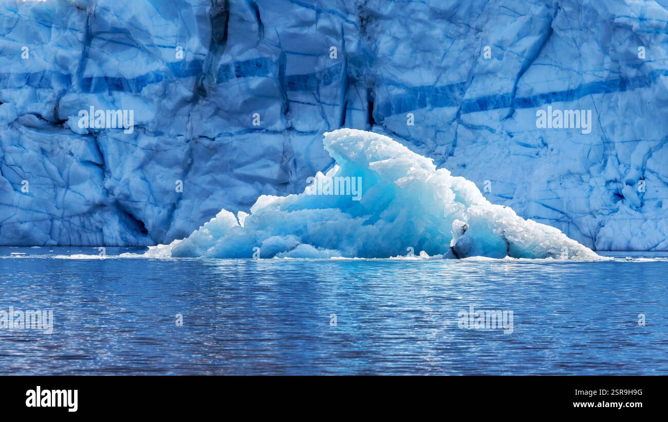 Blue iceberg against larger iceberg background in Northeast Greenland ...