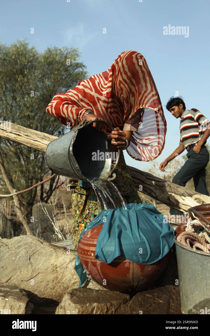 Rajasthani lady fetch drinking water from well pouring in pot ...