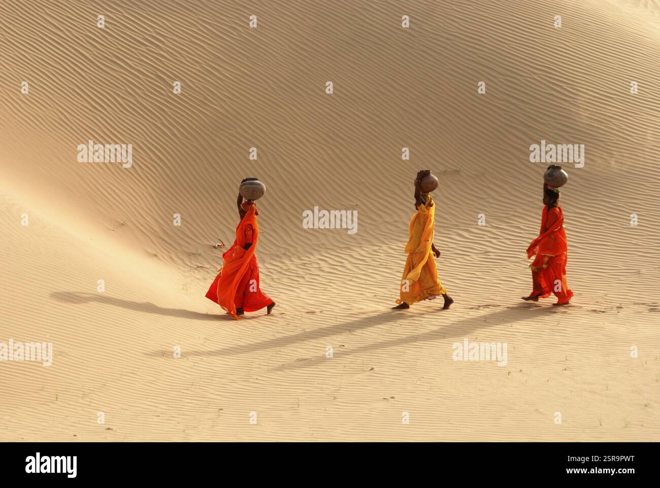 Rajasthani women with pitchers on head walking on sand dune of Khuri ...