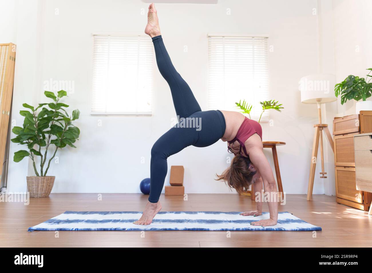 Senior Asian woman practicing Eka Pada Urdhva Dhanurasana One Legged ...