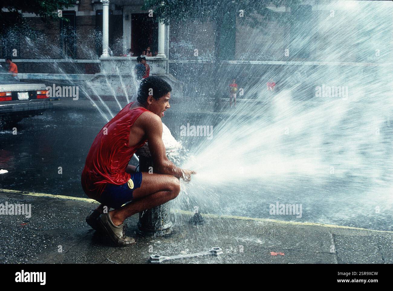 Teen adjusting the fire hydrant spray on a hot summer day in his ...