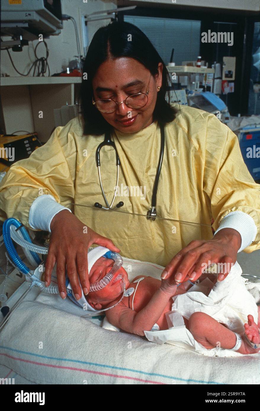 Premature baby on life support being cared for by a female nurse in the ...