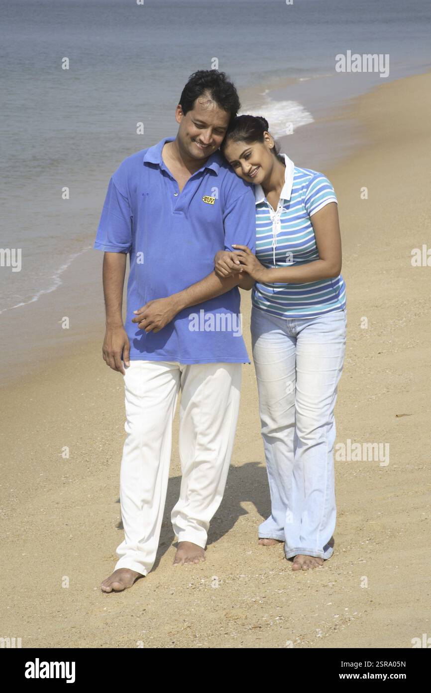 South Asian Indian young woman holding arm of man resting head on his shoulder standing on ...