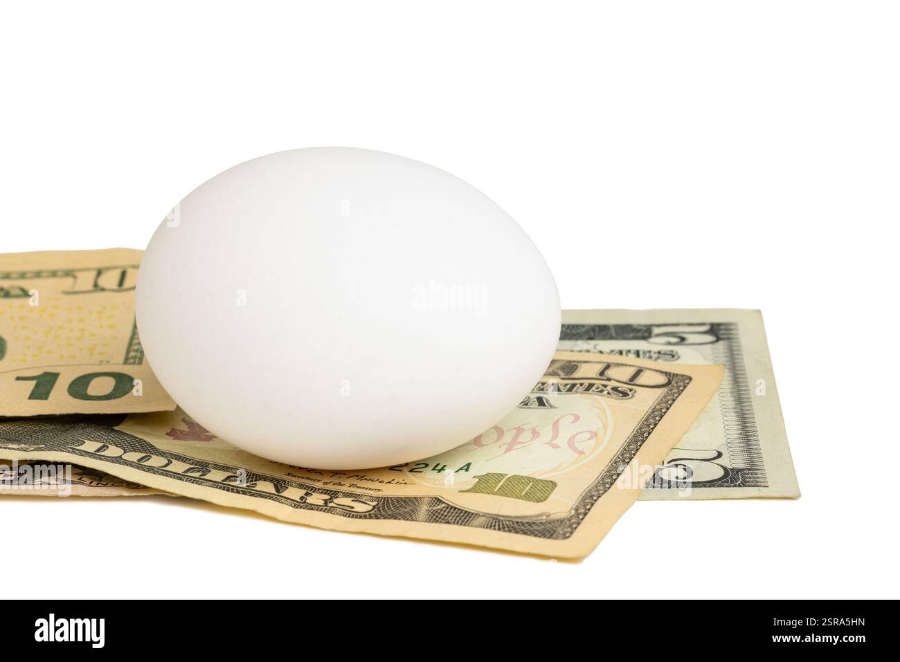 Egg Money - A single egg on five and ten dollar bills Stock Photo - Alamy