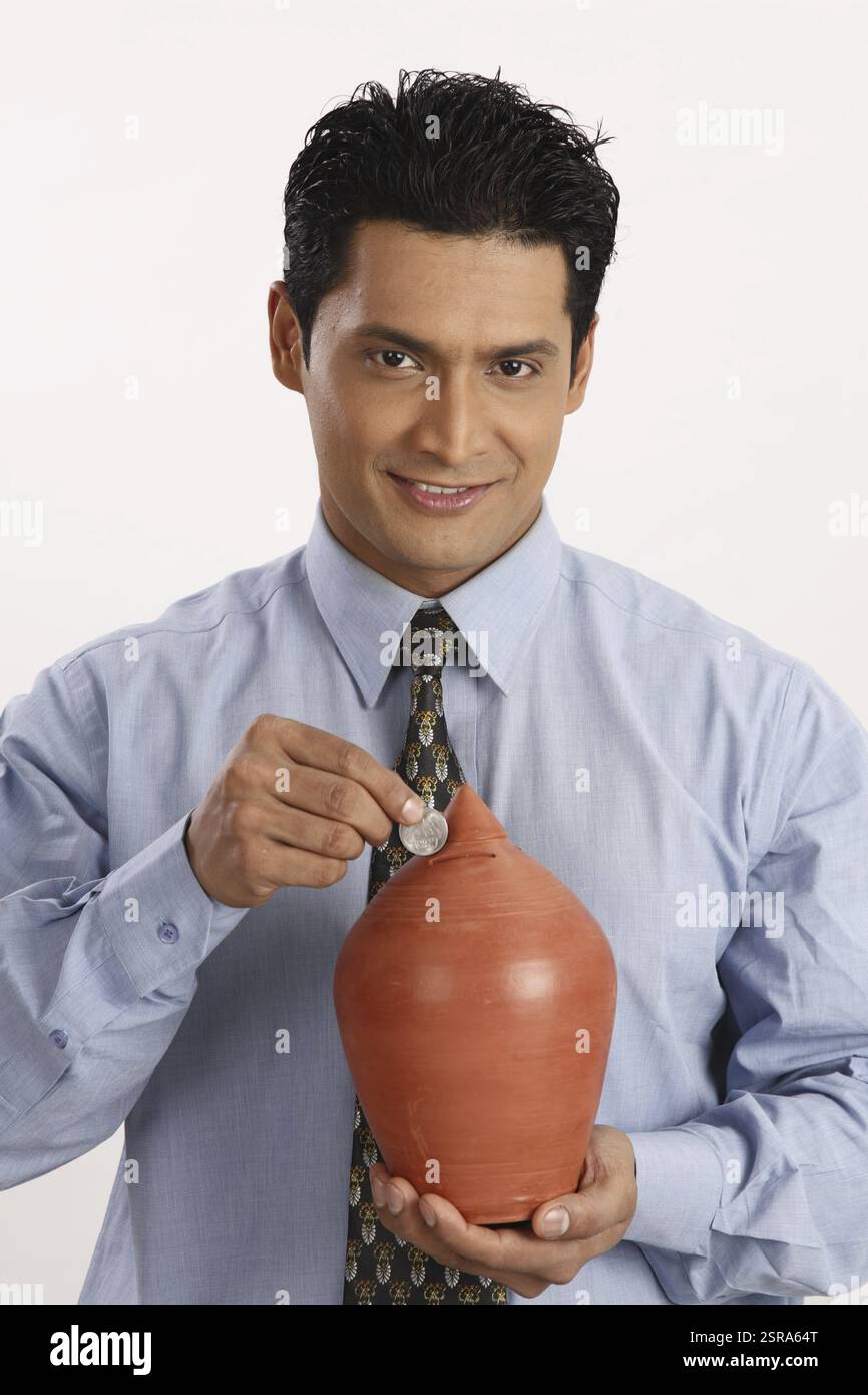 Businessman holding small saving earthen pot in one hand and putting ...