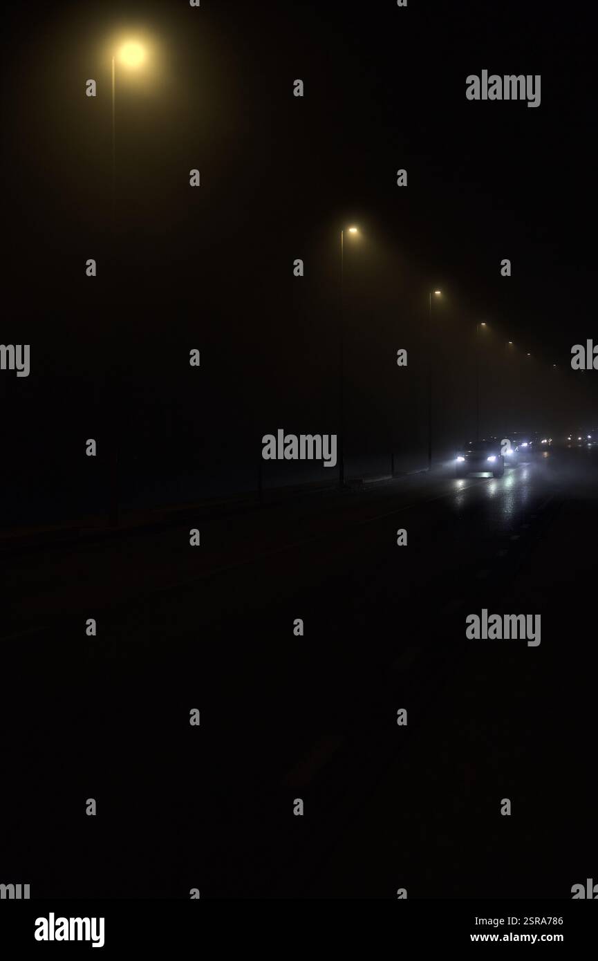 Road on a foggy night with lit street lamps and passing cars Stock ...