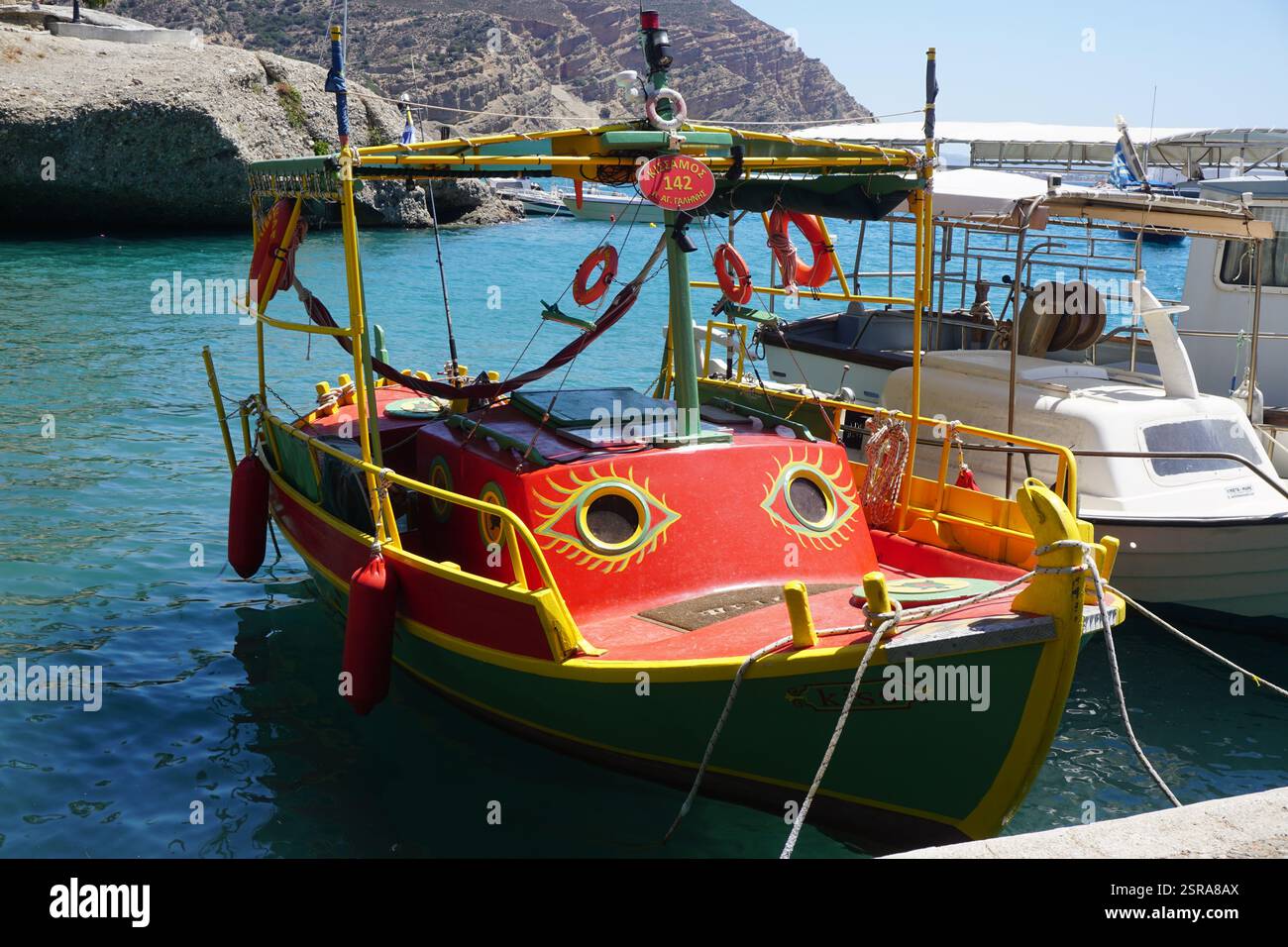 A vibrant fishing boat is secured with other vessels in the port. It ...