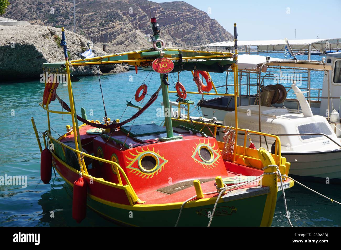 A vibrant fishing boat is secured with other vessels in the port. It ...