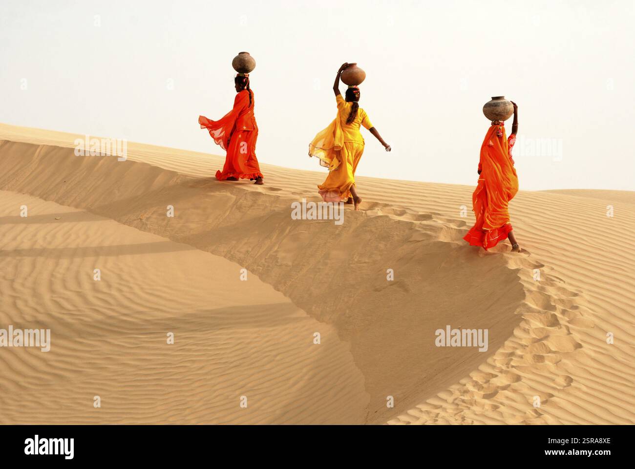 Rajasthani women with pitchers on head walking on sand dune of Khuri ...