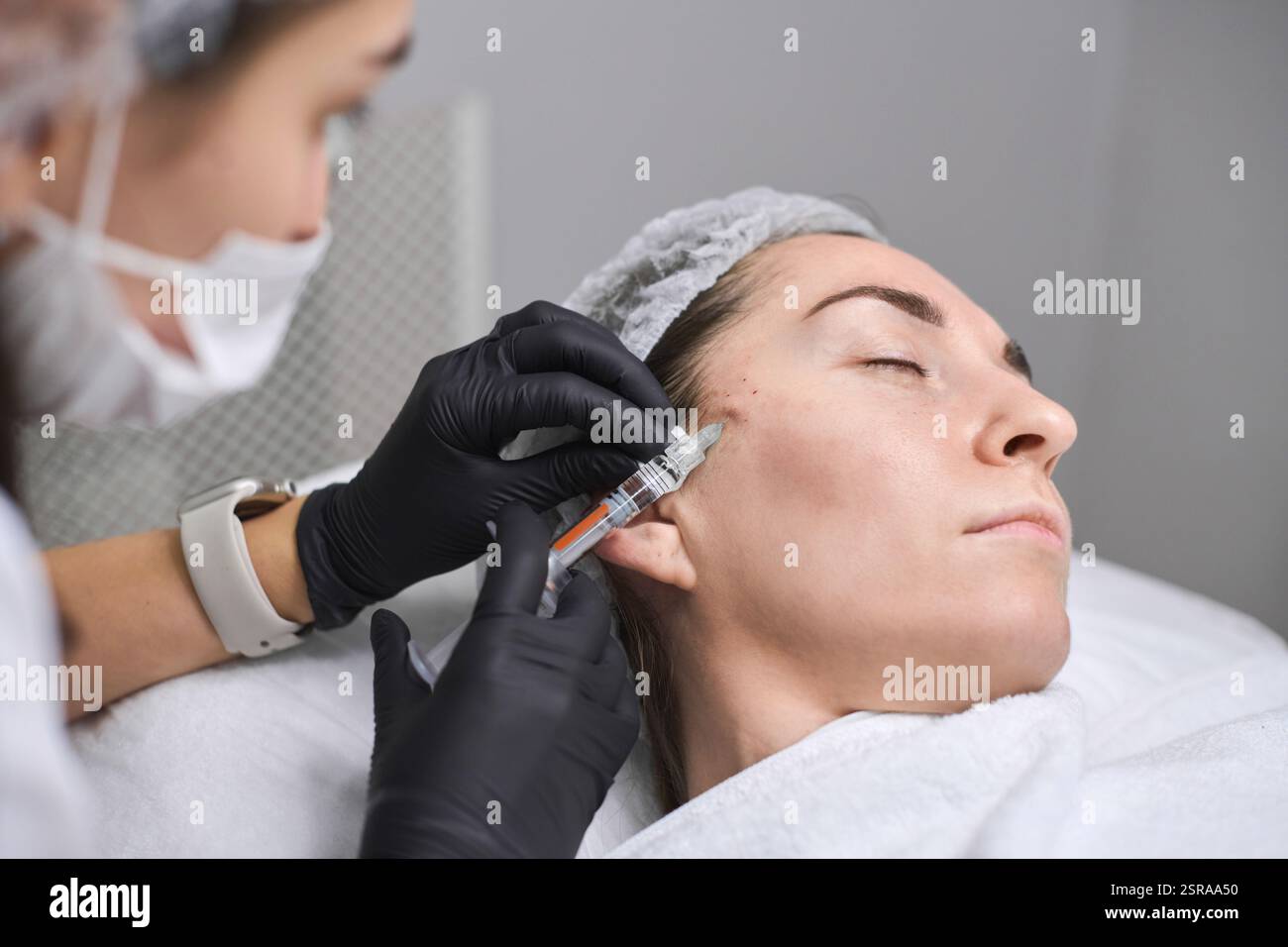 Young woman receives facial injection from professional in clinical ...