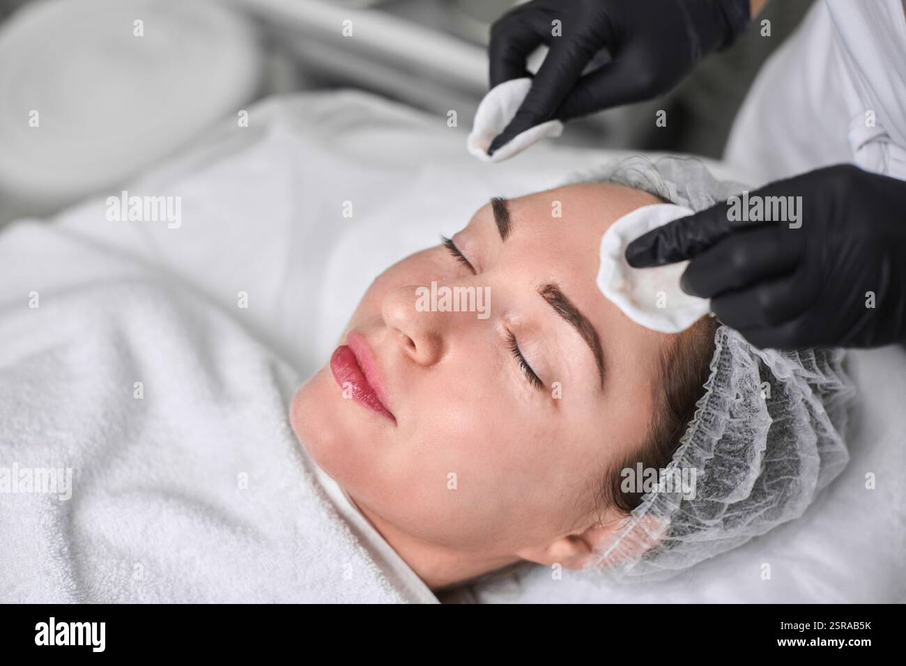 Young woman receives soothing facial treatment in spa. Atmosphere is ...