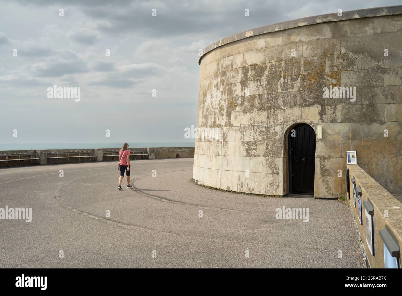 Woman walks by the circular, weathered stone structure, Seaford Museum ...