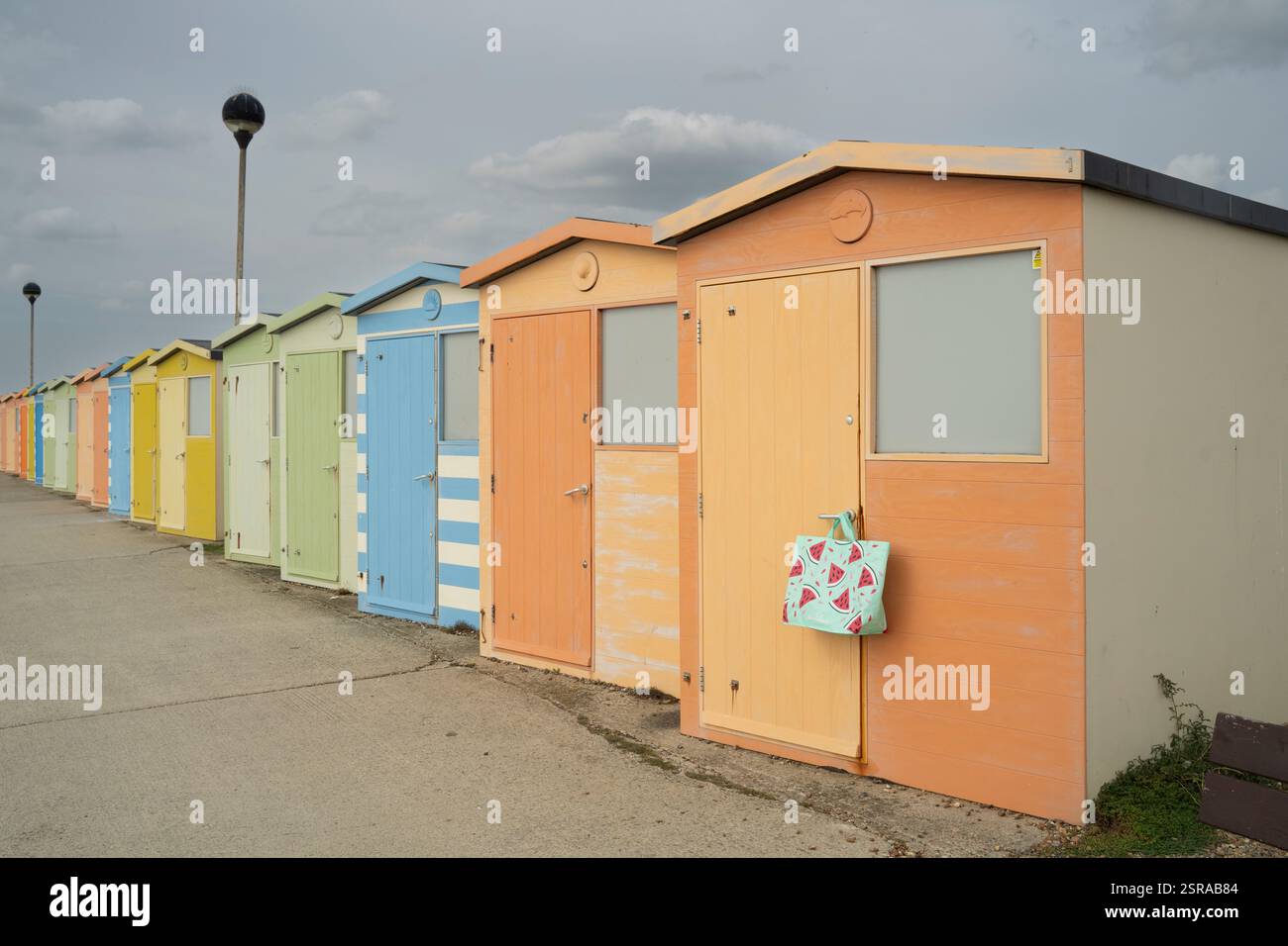 Colorful beach huts line the promenade at Seaford UK. A watermelon ...