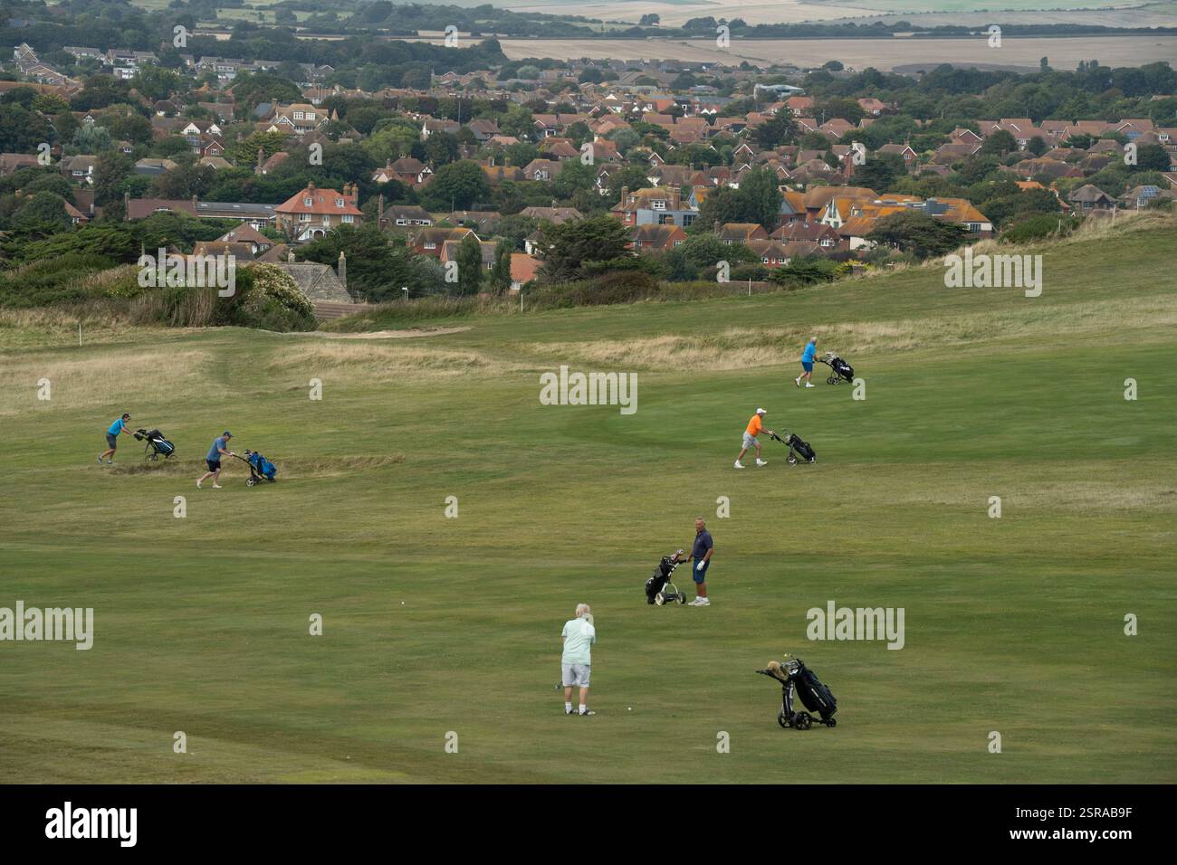 Golfers on the course above the town of Seaford, UK. Enjoying a game of ...
