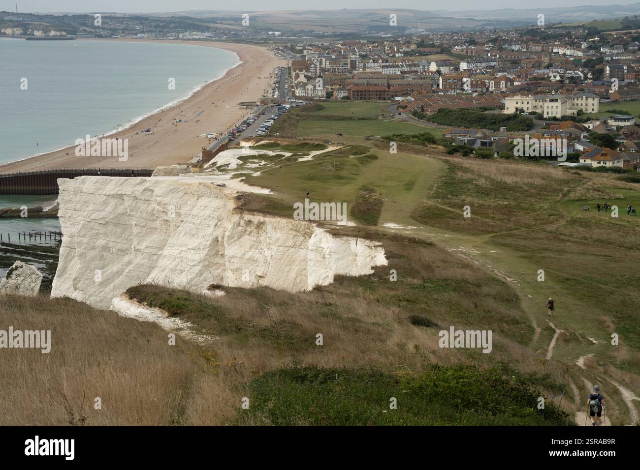 View of the white cliffs of Seaford, UK, with people on the beach below ...