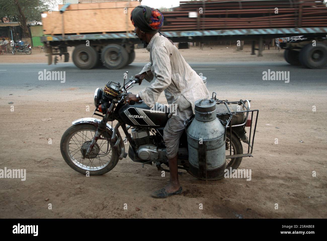 Rajasthani milkman carrying milk cans getting ready to start bike ...