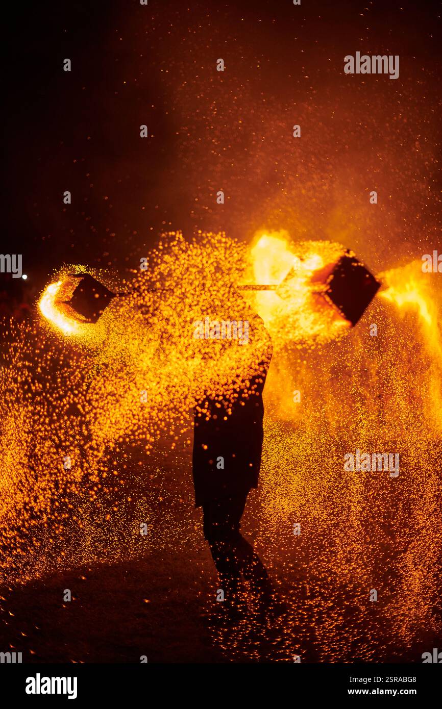 Silhouette of two fire performers with sparkling fire staff erupting in ...