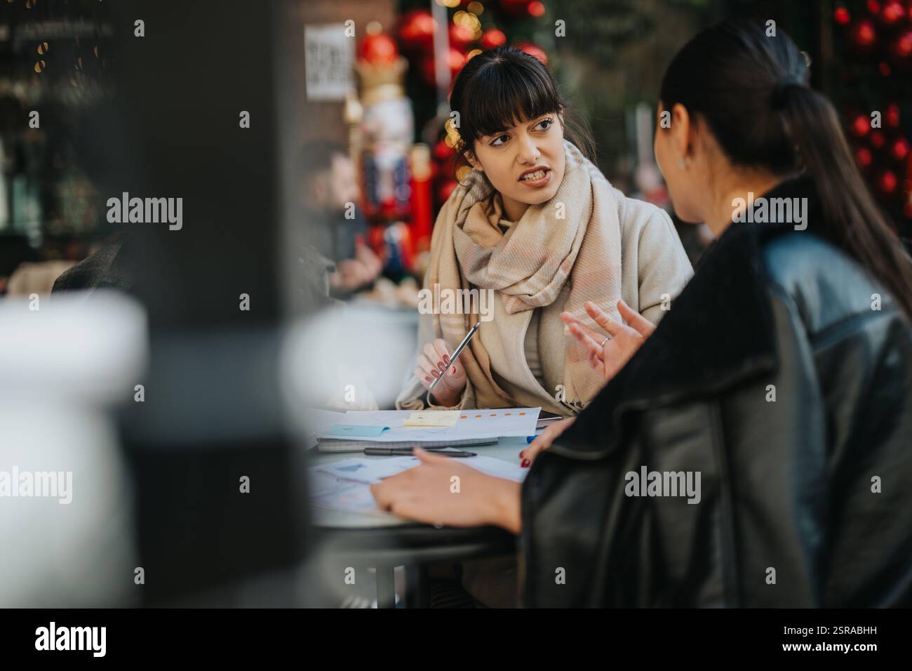 Two women discussing documents in an outdoor business meeting setting ...