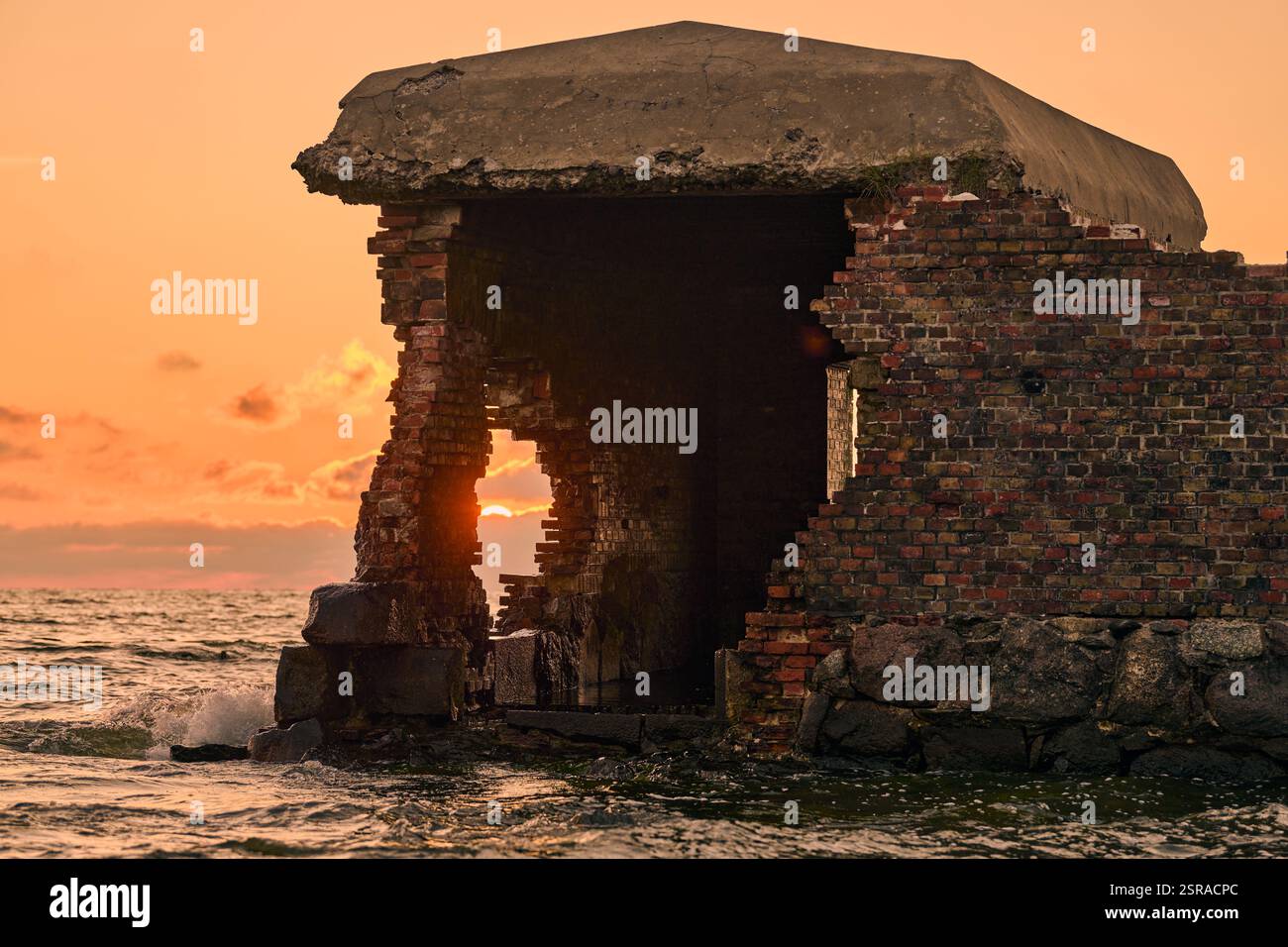 Ancient stone ruins bathed in sunset glow stand resilient against ocean ...