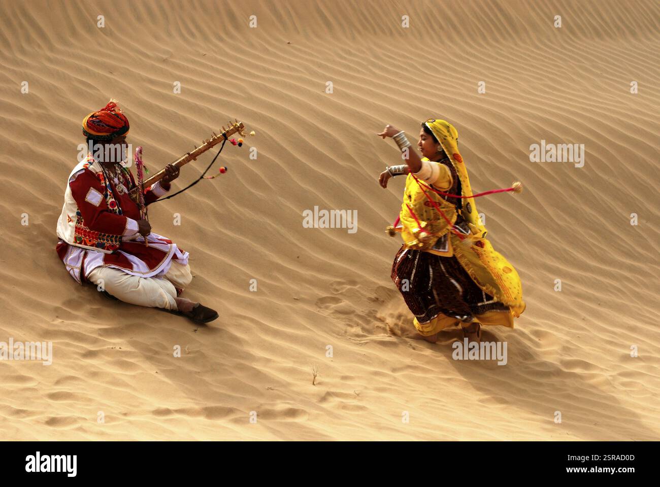 Rajasthani folk musician playing ravanhatta lady dancing on sand dune ...