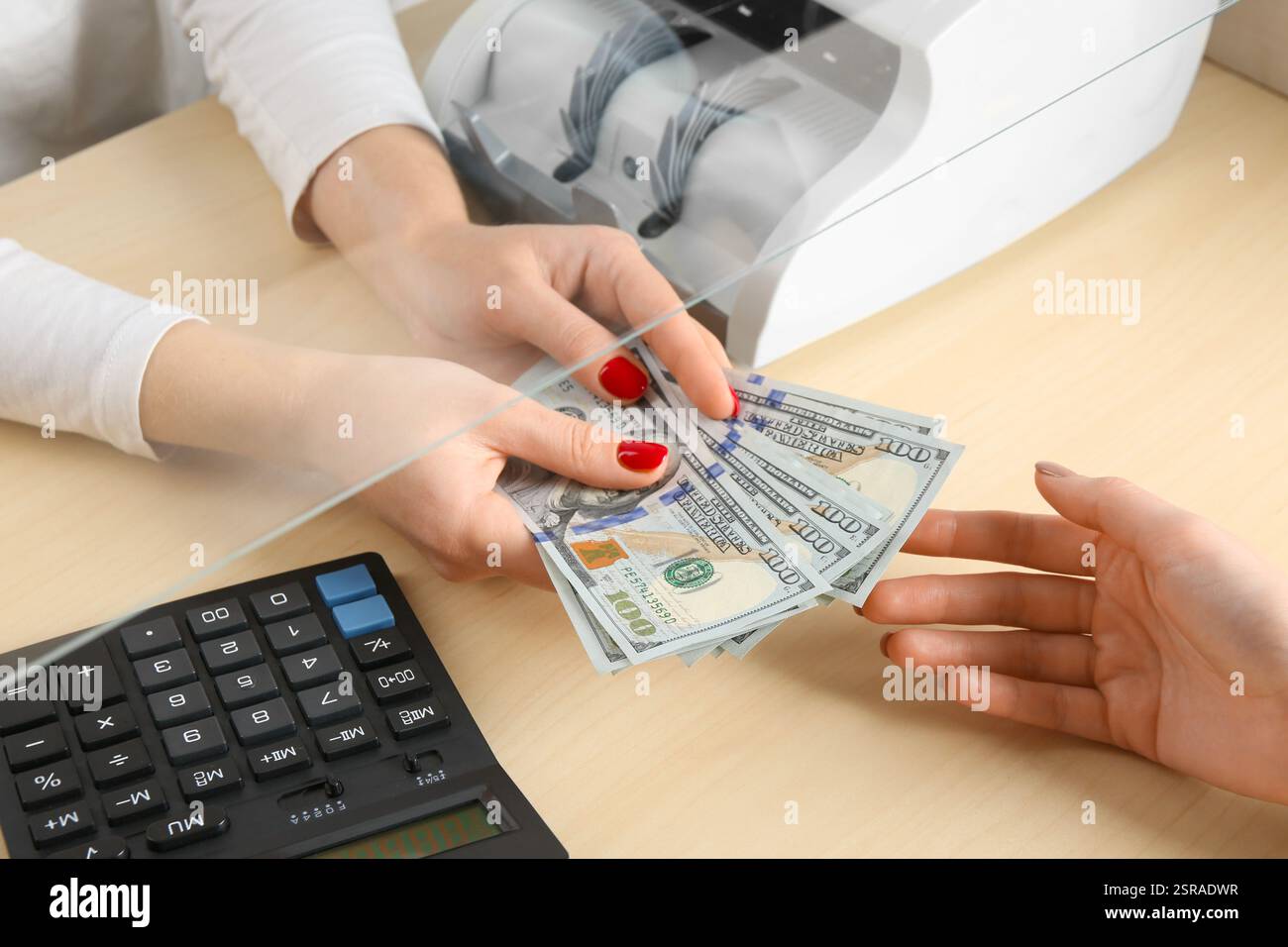 Cashier giving dollar banknotes to client at table in money exchange ...