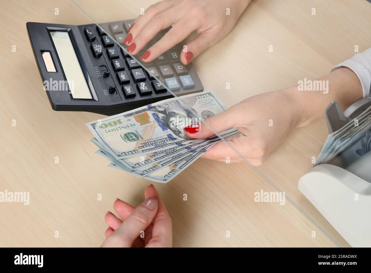 Cashier giving dollar banknotes to client at table in money exchange ...
