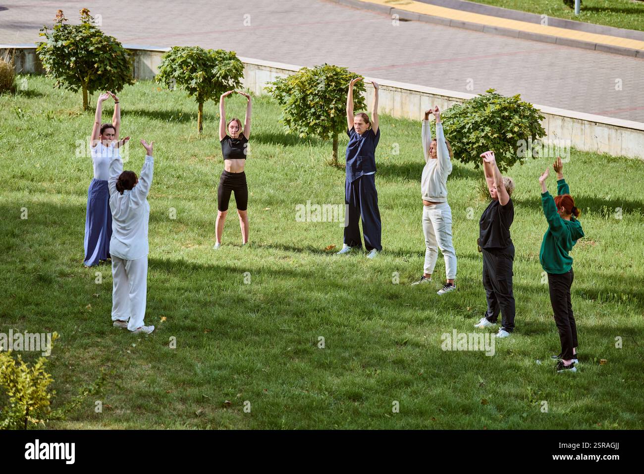 Adults of various ethnicities practicing qigong outdoors, bending ...