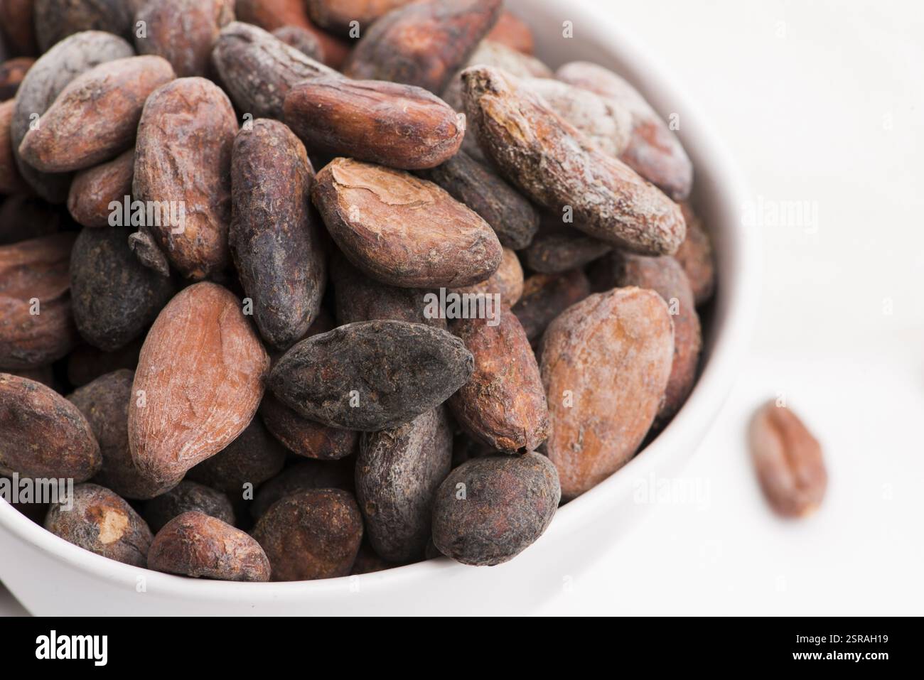 Bowl of cacao beans on a white background Stock Photo - Alamy