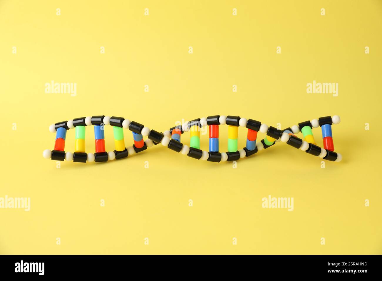 One DNA structure model on yellow background Stock Photo - Alamy