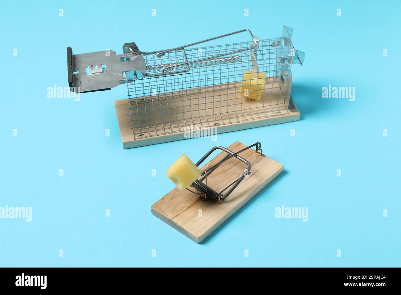 Two different mouse traps with bait on light blue background Stock ...