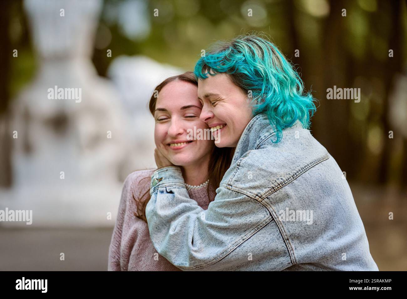 Young women, one with teal hair and one with brown hair, share joyful ...