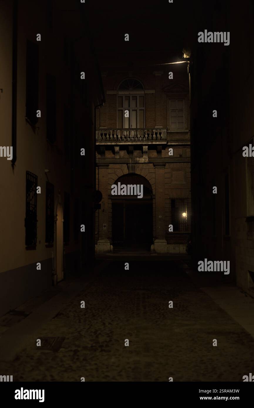 Alley in a town at night with buildings framing the entrance of a ...