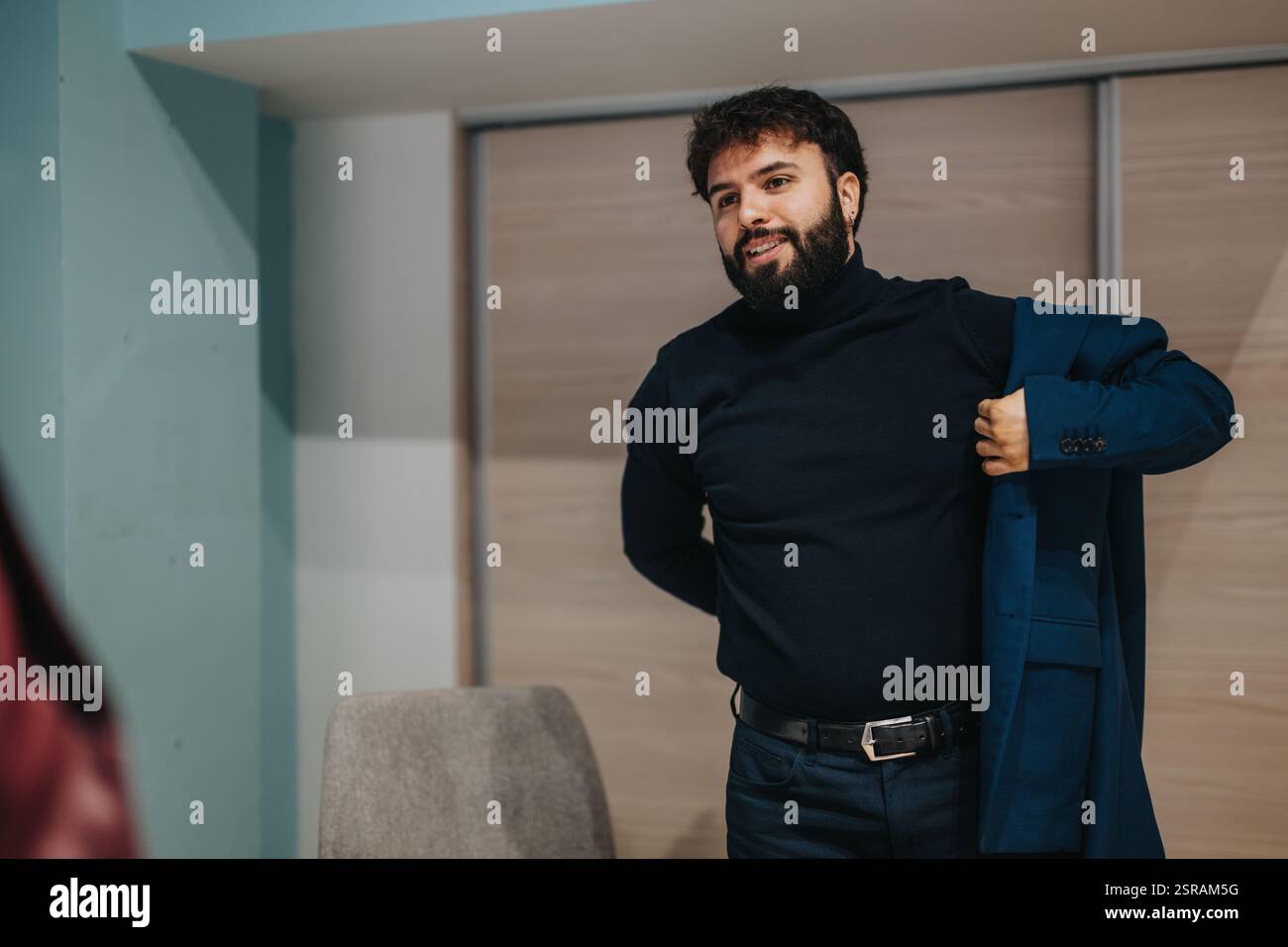 Confident Man Dressed Stylishly Puts on a Jacket in a Modern Room Stock ...