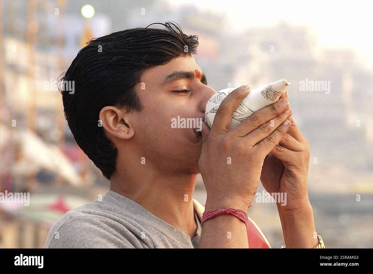 Man blowing conch shell on Ganga ghat, varanasi, uttar pradesh, india ...