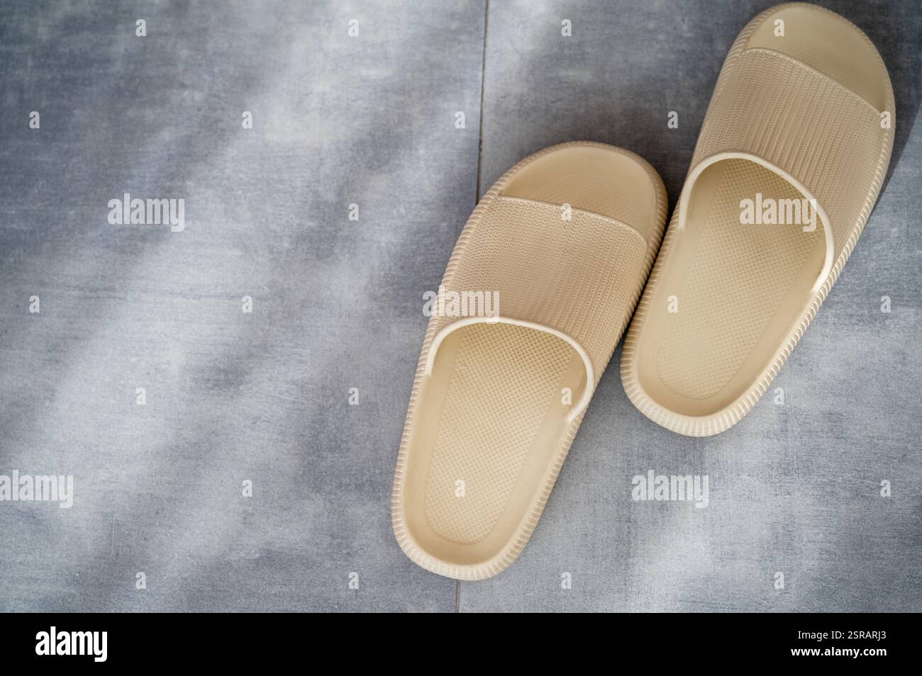 one pair of beige rubber slippers stand on the gray granite floor Stock ...